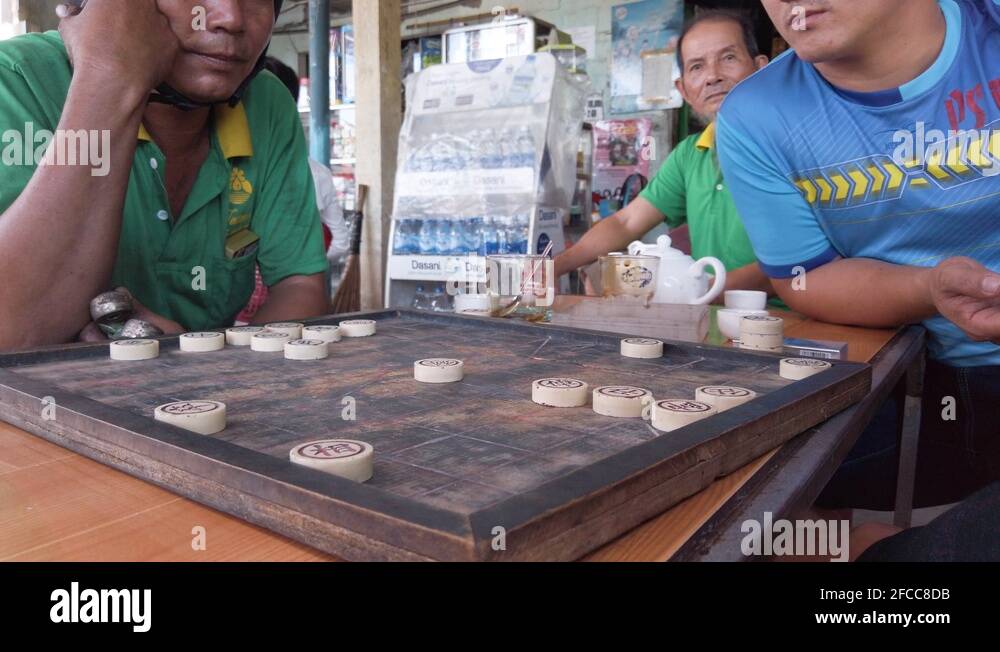 Chinese Chess, Xiangqi. Asiatic people play in a bar on a wood board ...