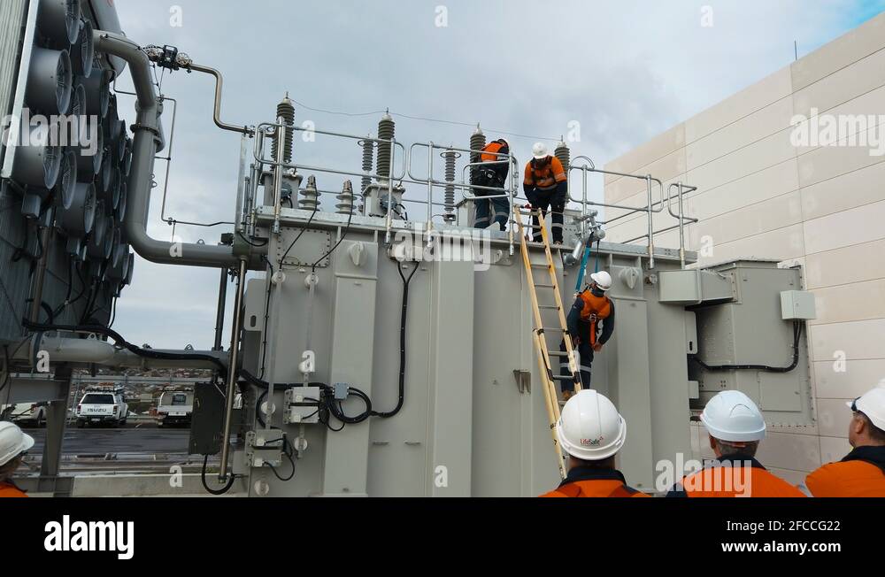 A group of electrical workers completing a transformer access and ...
