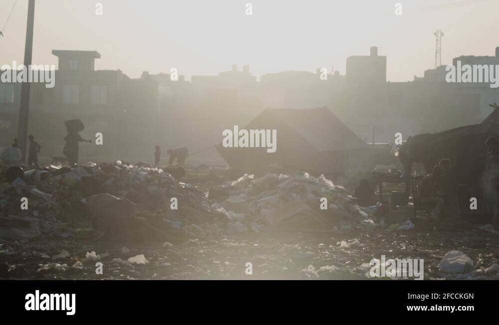 People Walk Amongst Dumped Garbage In The Slums, Backlit Morning Sun ...