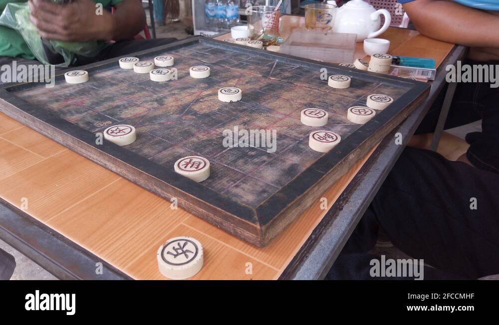 Chinese Chess, Xiangqi. Asiatic people play in a bar on a wood board ...