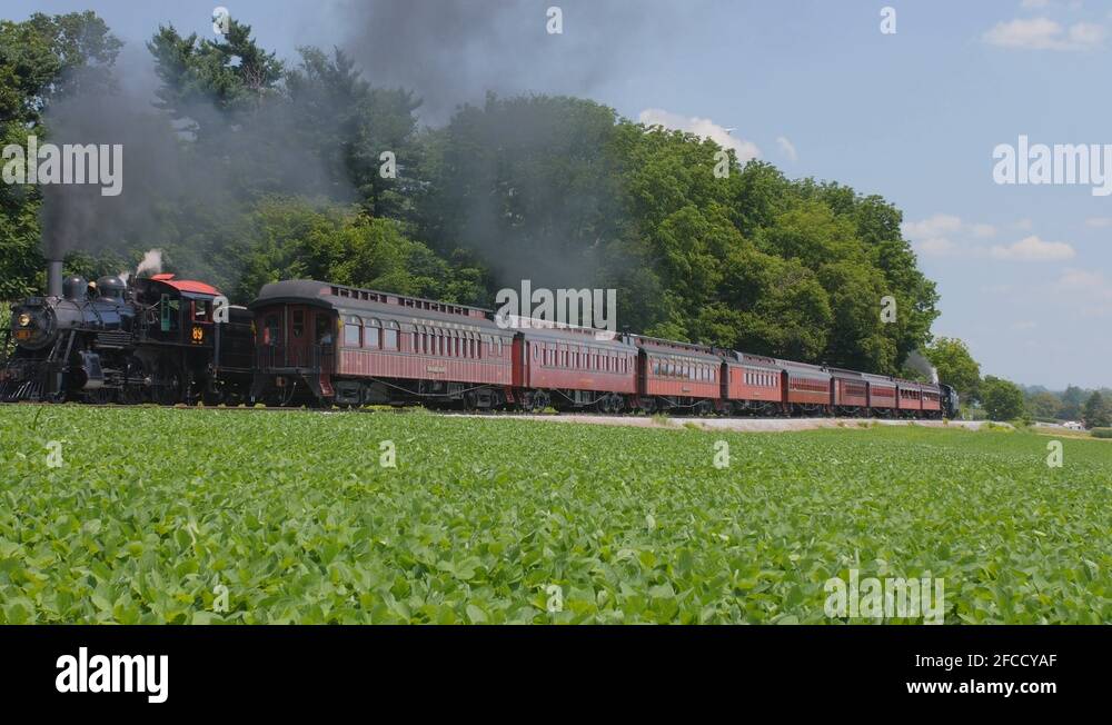 A 1910 Steam Engine with Passenger Train Pulling into a Station Puffing ...