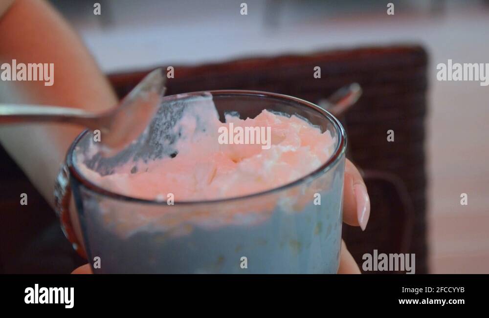 Girl eating whipped cream from the top of the coffee with a long silver ...