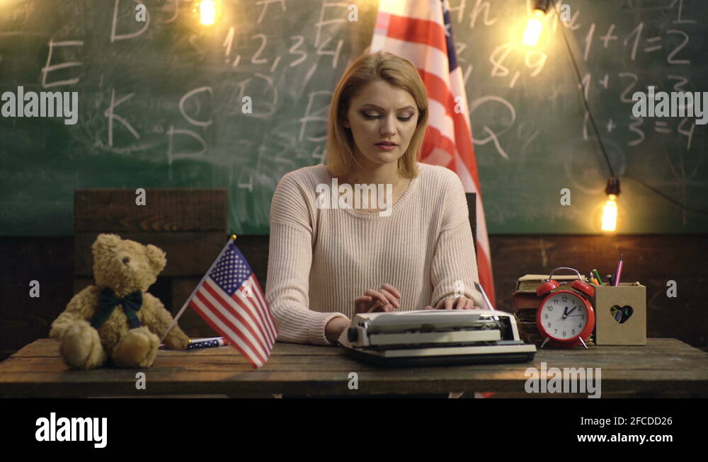 Woman typing on typewriter in classroom, American flag background ...