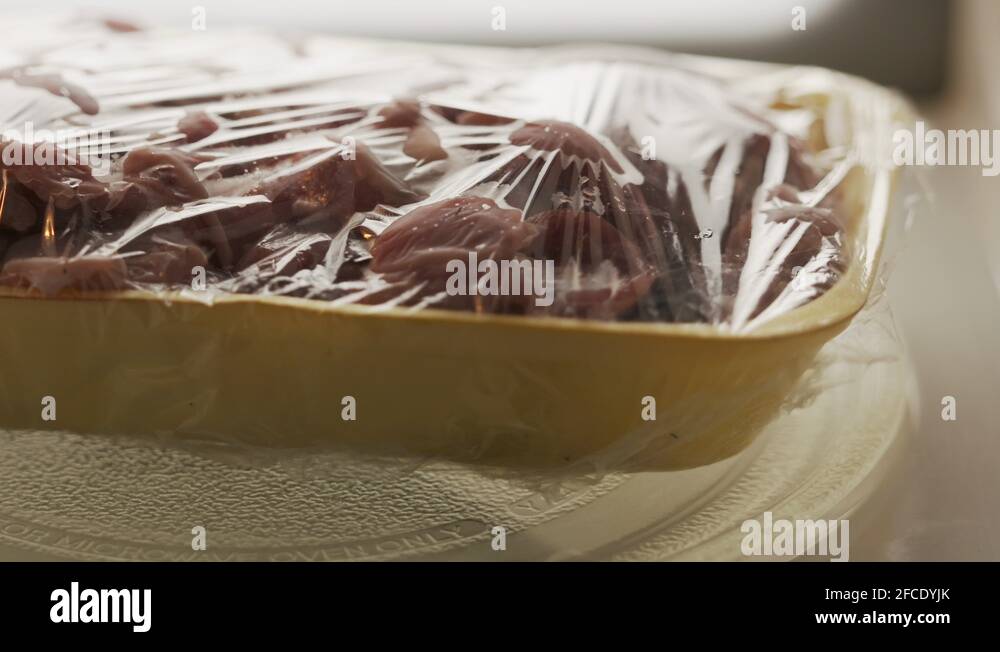 Fresh raw сhicken offal in food tray with plastic wrap rotating in ...