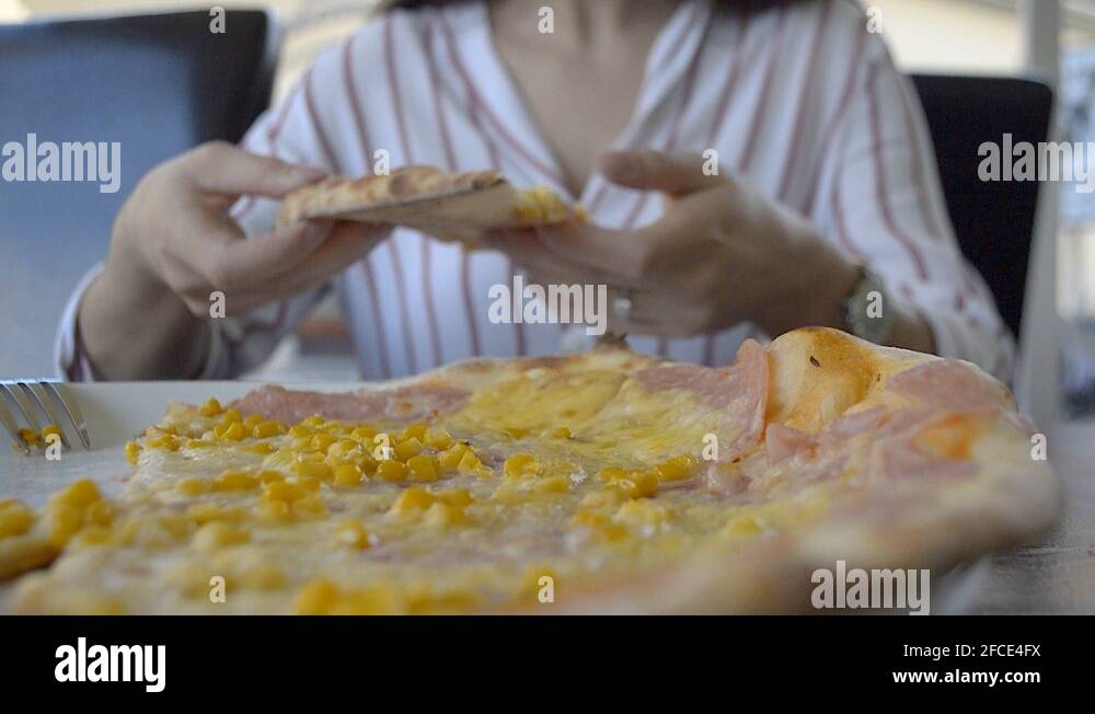 Girl out of focus eating a slice of a huge pizza in front of her, TILT ...