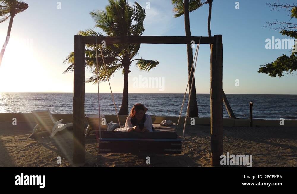 Female resting on exotic beach rope swing Fiji. Paradise silhouette ...