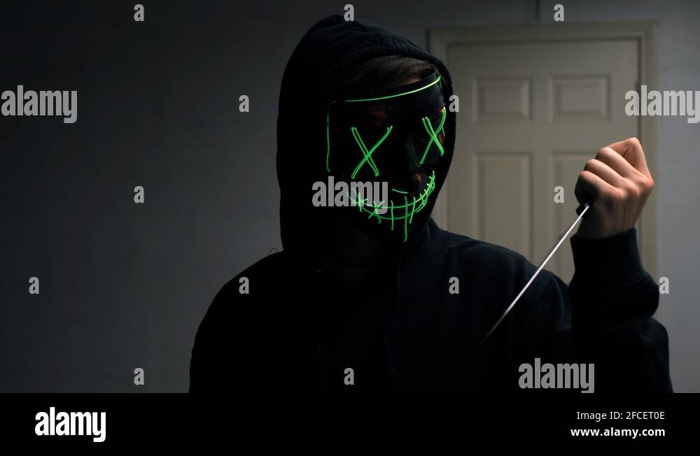 A scary slasher killer in a generic anonymous halloween mask holding a ...