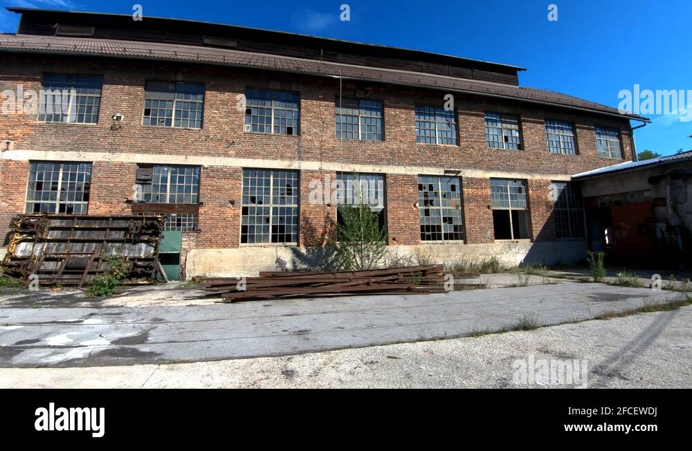 4K Forwarding tilt up abandoned government brick warehouse on bright ...