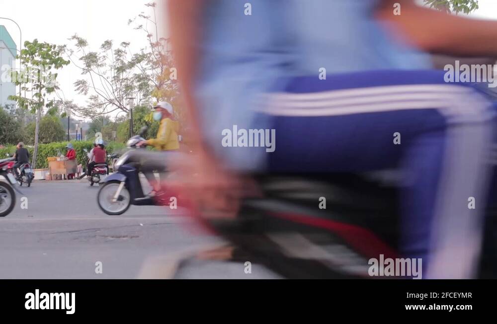 A huge crowd of people riding on Vietnamese street on mopeds and ...