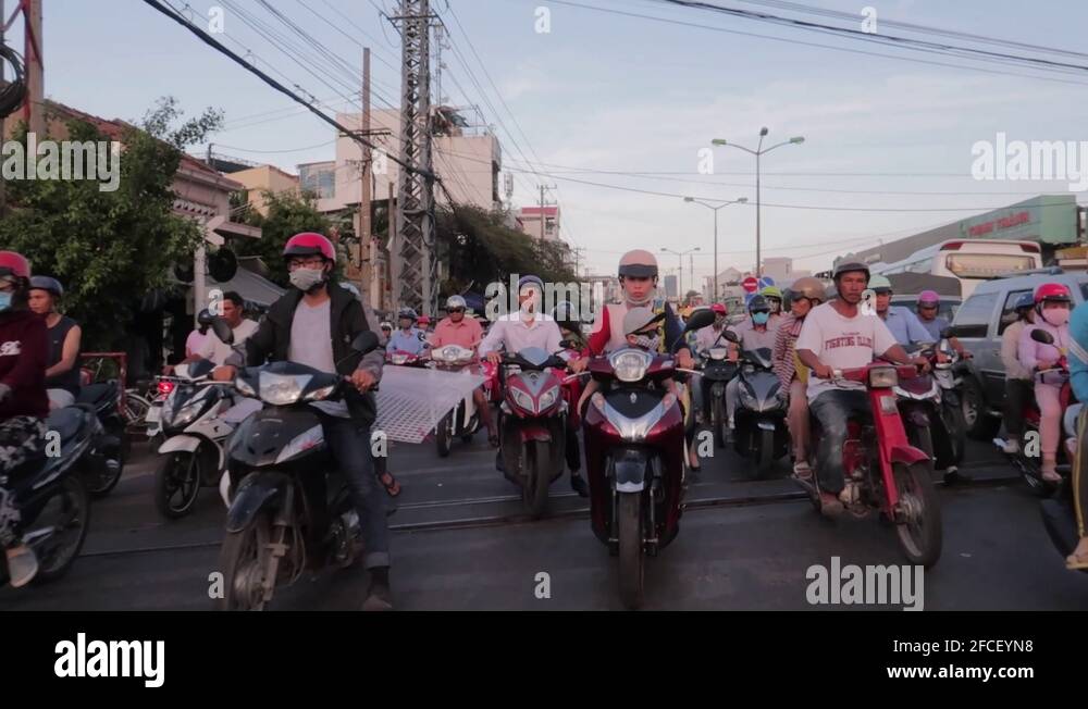 A huge crowd of people riding on Vietnamese street on mopeds and ...