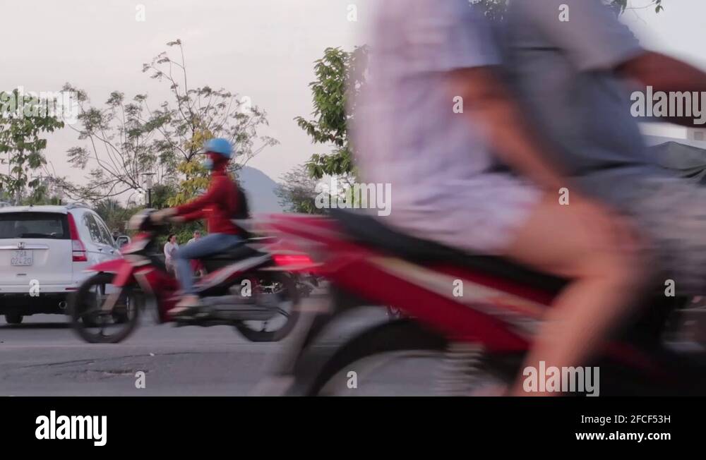 A huge crowd of people riding on Vietnamese street on mopeds and ...