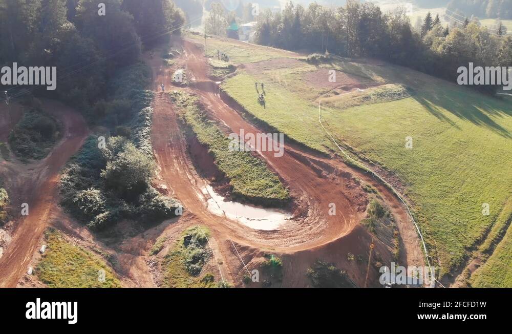 Motocross park with rider jumping over a big jump. Watered track in ...