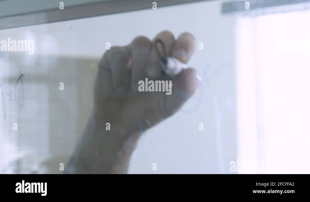 A teacher or a student writing math formulas on a transparent glass ...