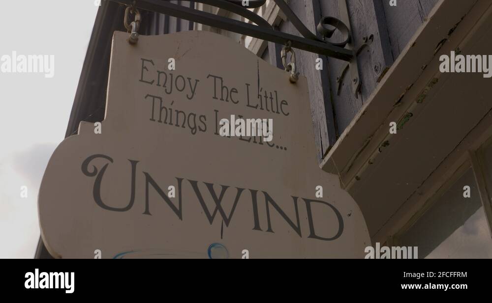 Pan down from a shop sign to the streetscape in the scenic small town ...