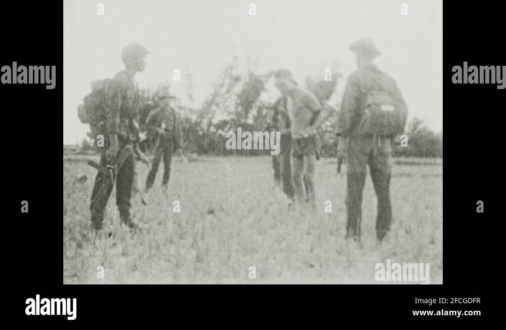 1960s: VIETNAM: prisoner on ground. Soldiers point gun at man's head ...
