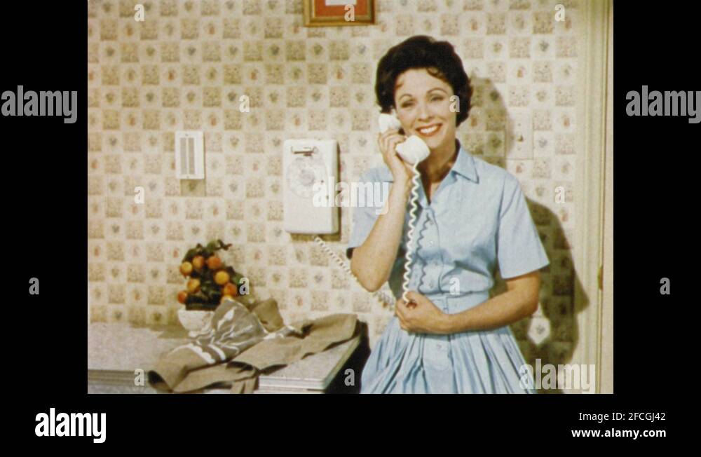 1950s: UNITED STATES: man speaks on telephone. Lady puts down telephone ...