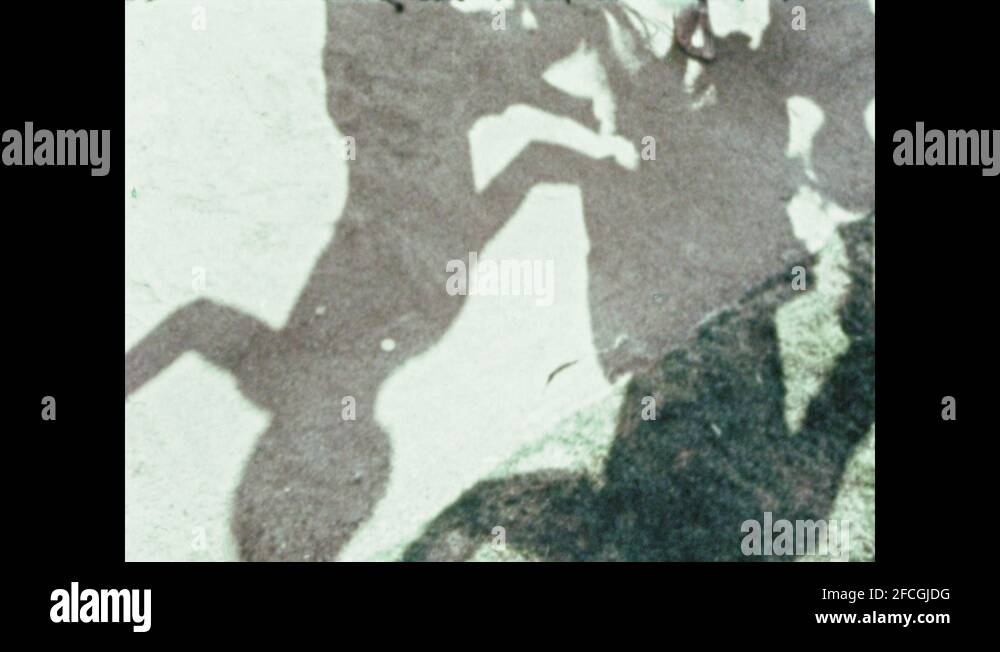 1970s: AFRICA: shadow of African people dancing. Men kneel on ground ...