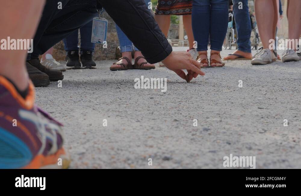 Tour guide drawing a map on the floor, showing something to his ...