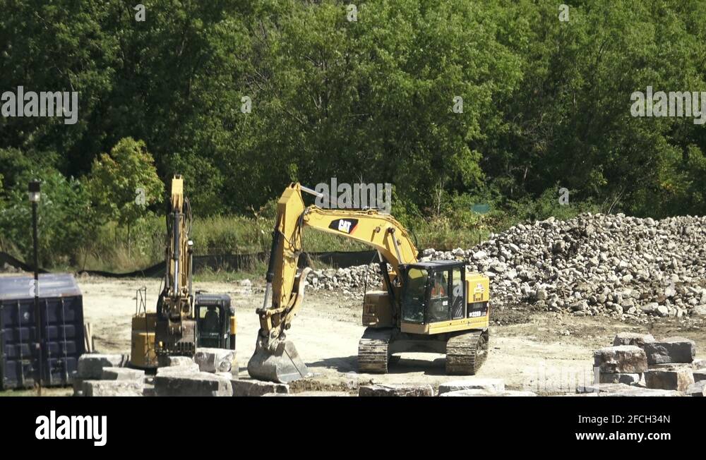 Excavator moving rock boulders in a construction project site Stock ...