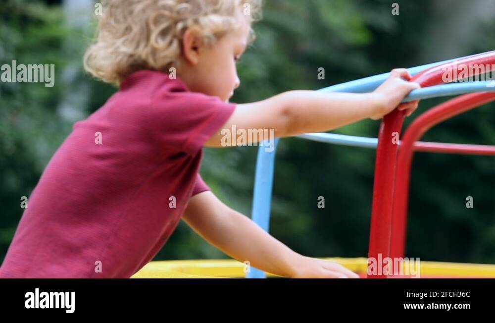 Child boy spinning around carousel at playground outside Stock Video ...
