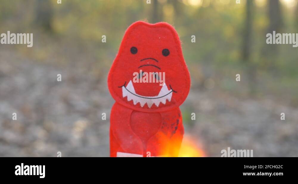 Red felt t-rex finger puppet on fire and melting in the woods Stock ...