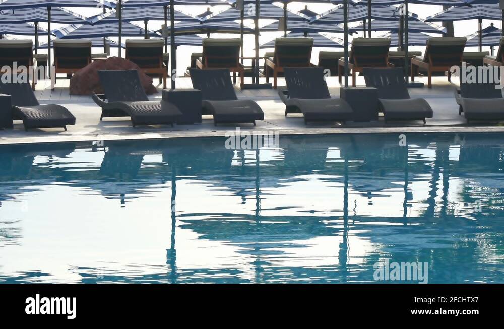 Empty poolside lounge chairs on deck near swimming pool. Static Stock ...