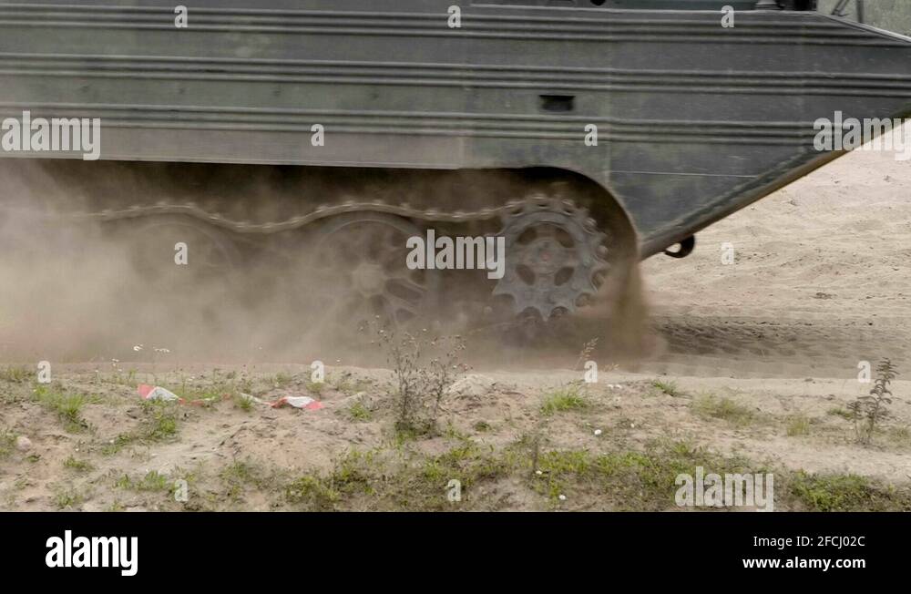 Military vehicle tracks close up leaving dust cloud from dirt track ...