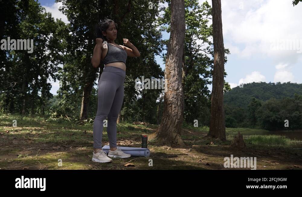 Fit indian girl in sportswear warming up under the shining sun before ...
