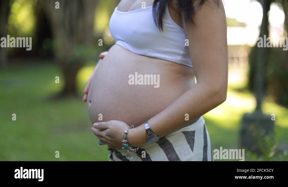 Pregnant Woman Standing Outside In Nature Caressing Belly Dreamy