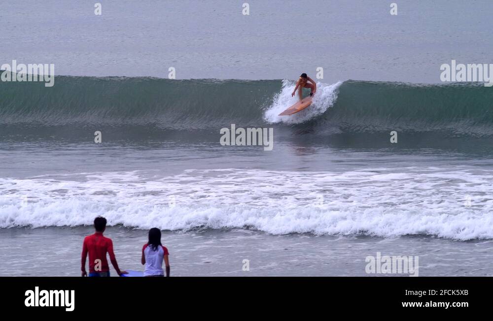 Young woman swimming with a large ocean wave on surfboard and falling ...