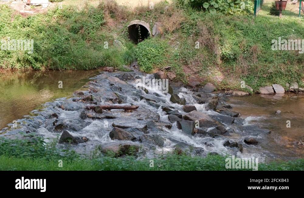 Sewage pipe outflow into river, water pollution and ecology concept ...