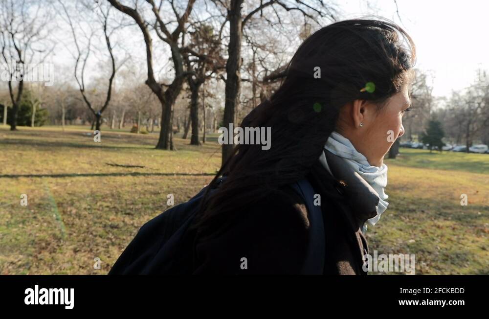Woman walking in slow-motion at park during cold season and sunset lens ...