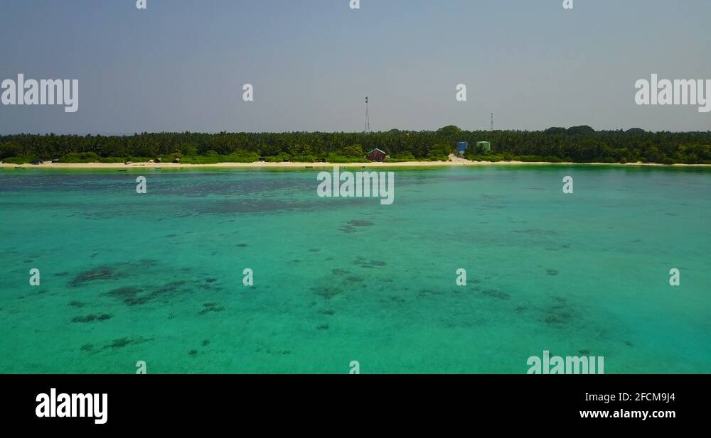 Droneing towards an exotic island with a barn / farm on the coast and ...