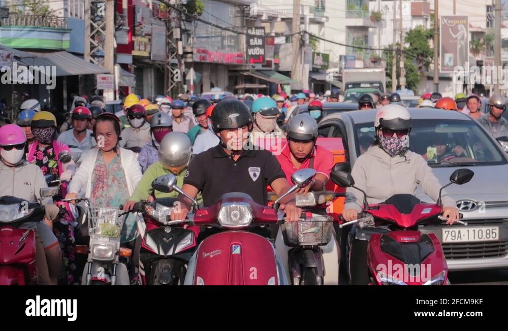 A huge crowd of people riding on Vietnamese street on mopeds and ...