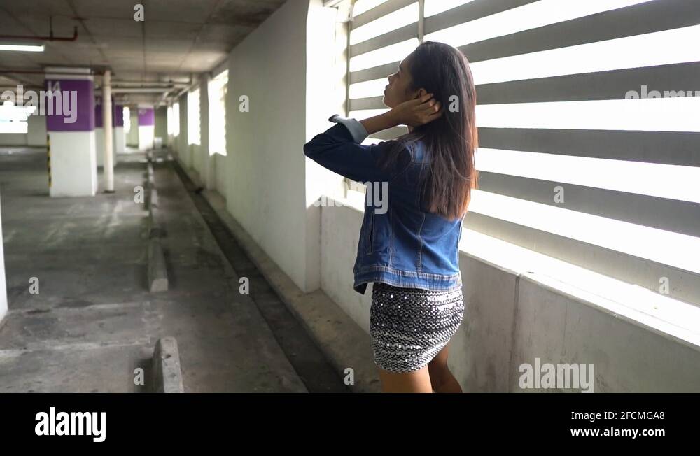 Sexy, young Asian woman with a smoldering look poses in front of a ...