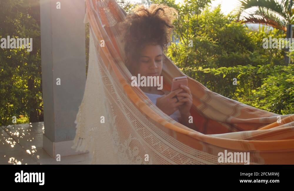 girl lying down in hammock stretched her arms to take picture, medium ...