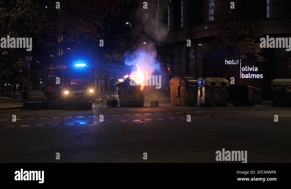 Firefighter extinguishing a burning dumpster on a street barricade with ...