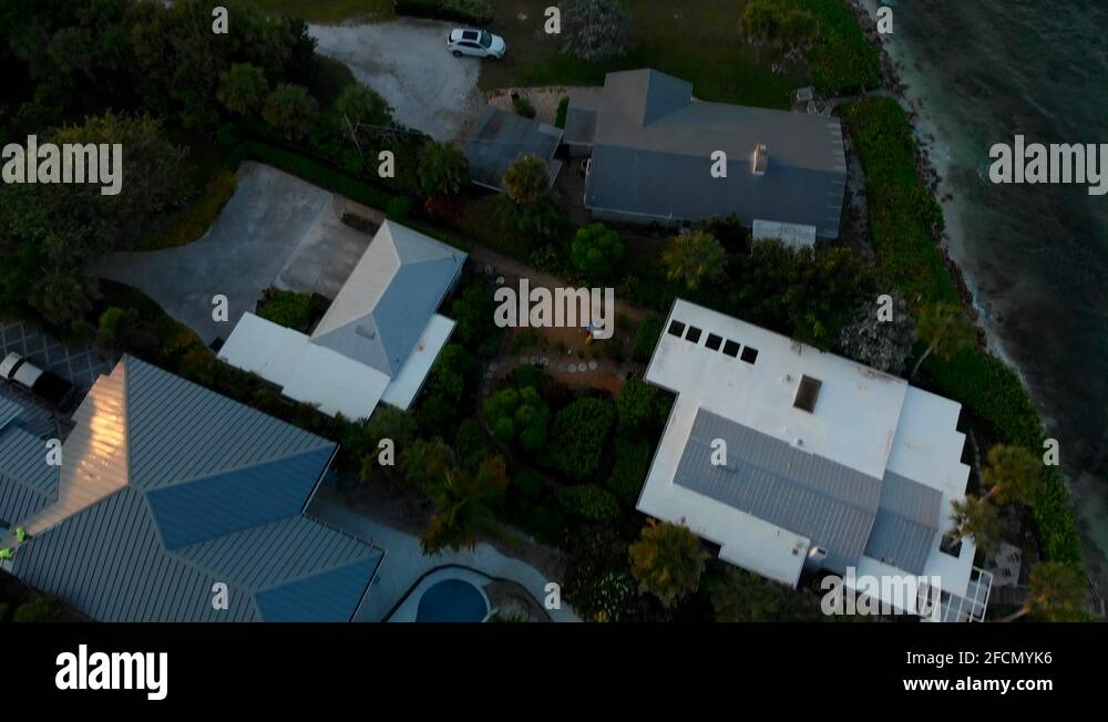 Aerial, beachfront homes from straight above, forward tilt up revealing ...