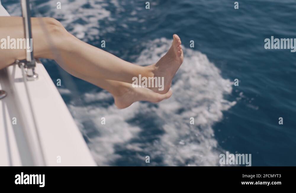 Female legs hanging from the yacht. The yacht moves along the waves ...