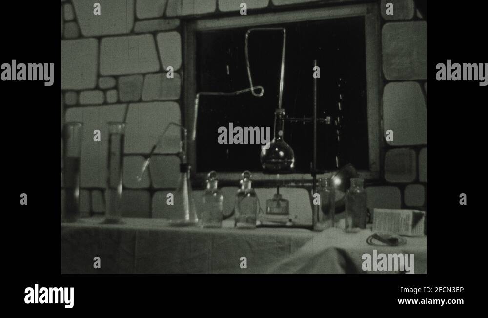 1930s: UNITED STATES: man in science lab. Man carries heavy object in ...