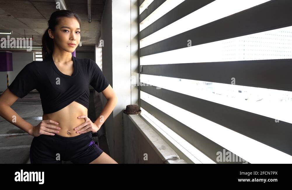 Sexy Asian woman with pierced belly button has a sultry look as she ...