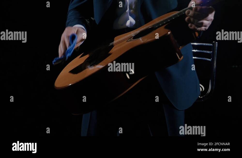 A musician with an acoustic guitar is getting ready to perform on stage ...