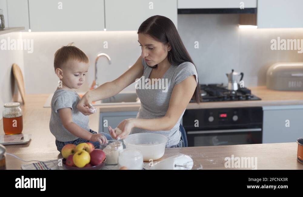 Cute little boy toddler and his mother is cooking in the modern kitchen ...