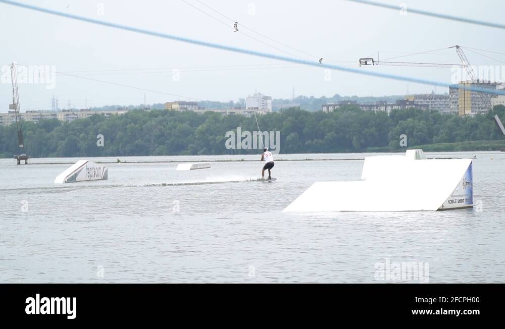 Water sport, wakeboarder is jumping and sliding on a rail, tricks and ...
