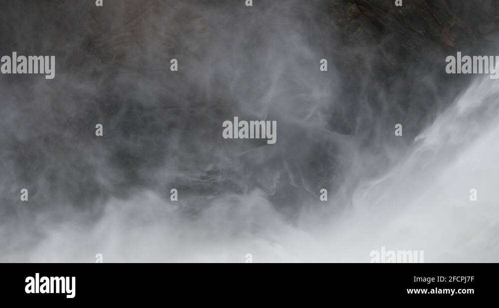 Waterfall and vapor splashing against rock walls creating organic ...