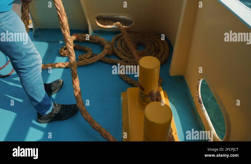 Close up of a man releasing the manila rope before he ties the vessel ...