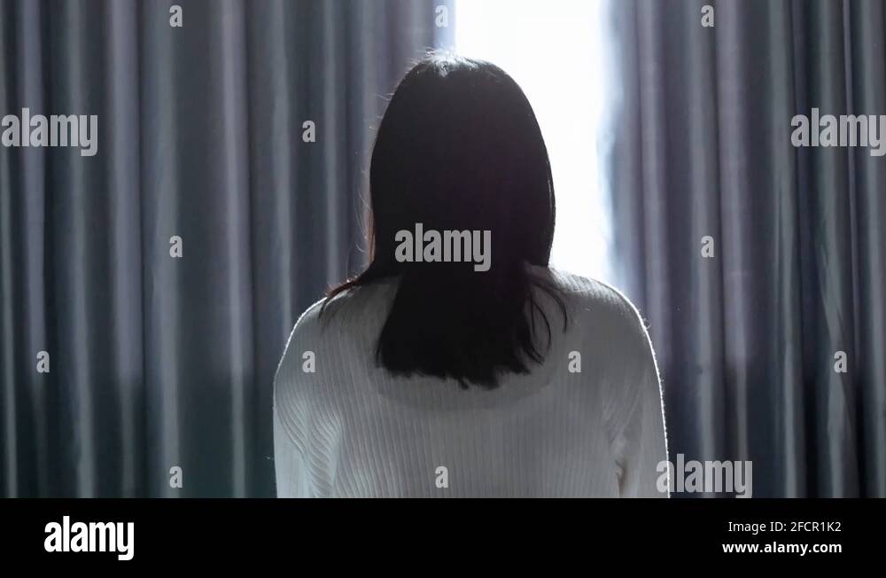 Rear of an Asian woman sitting and stretch lazily in the bright morning ...