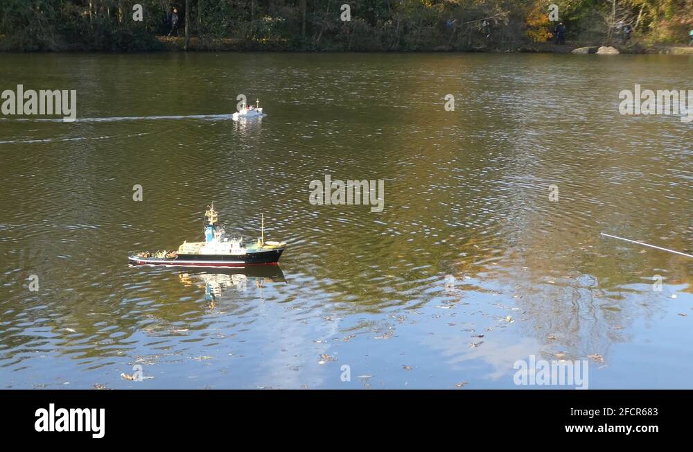 Electronic remote controlled miniature toy motorized boat on calm park ...