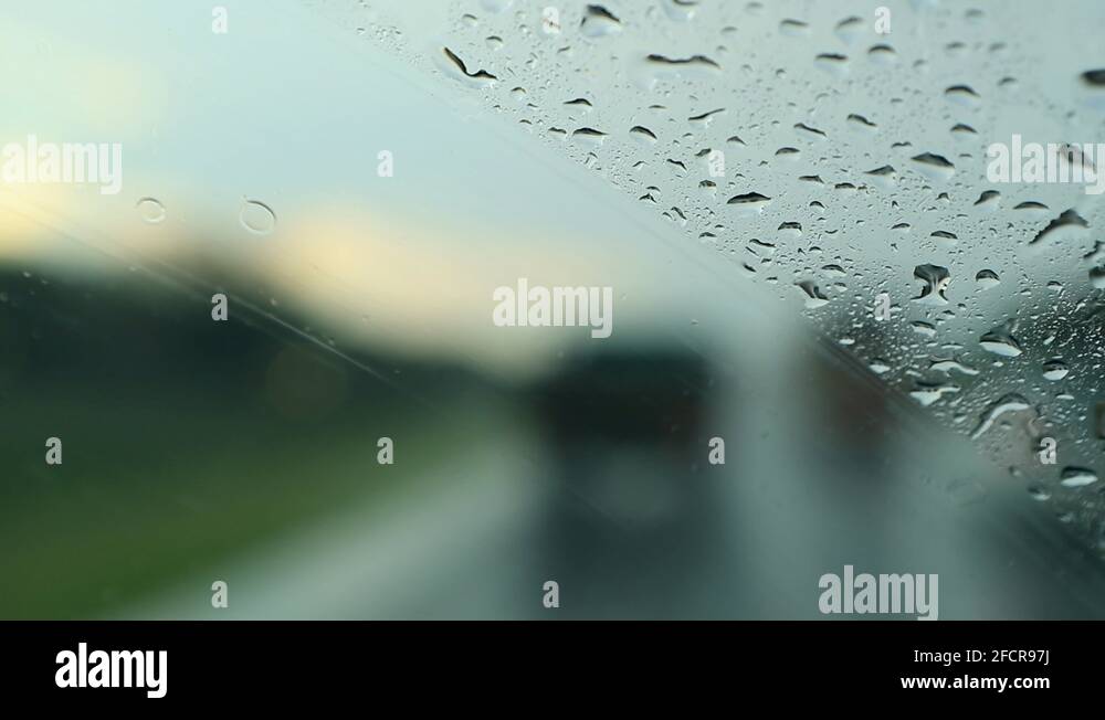 Windshield swiping droplets from window. POV of passenger on road trip ...
