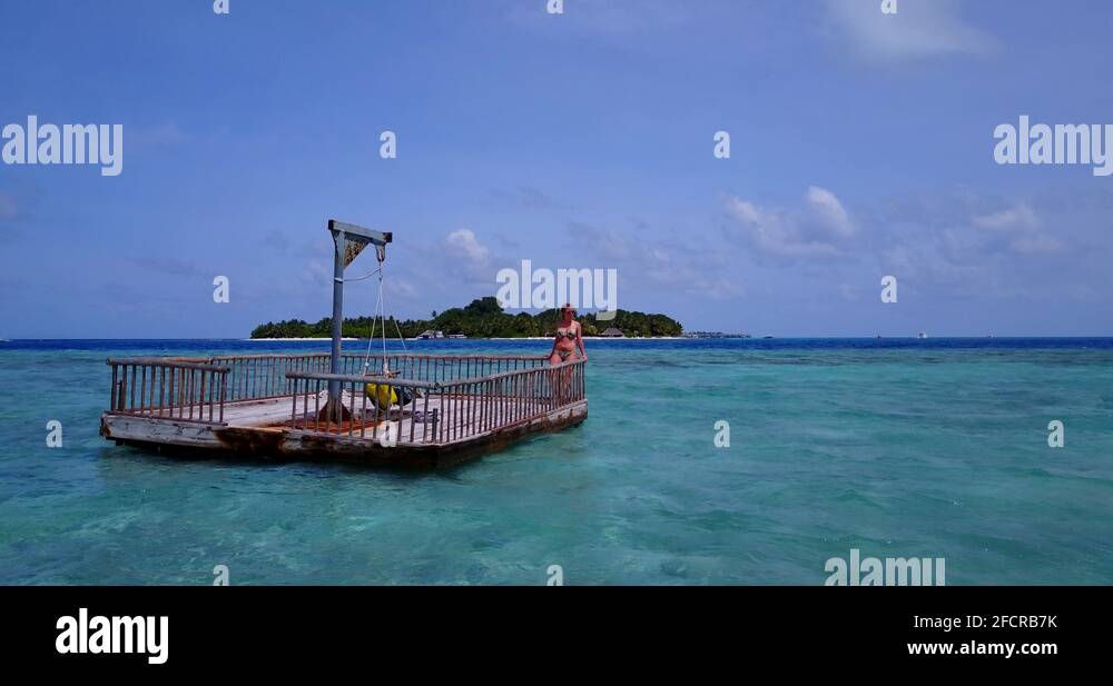 Girl in bikini on a floating platform over crystal sea water, watching ...
